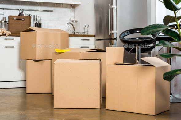 interior of modern kitchen with cardboard boxes during relocation at ...