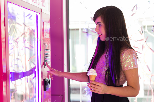 Pretty young woman using a modern beverage vending machine. Her hand is ...