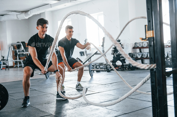Young people with sportive body shapes doing crossfit by using knots ...
