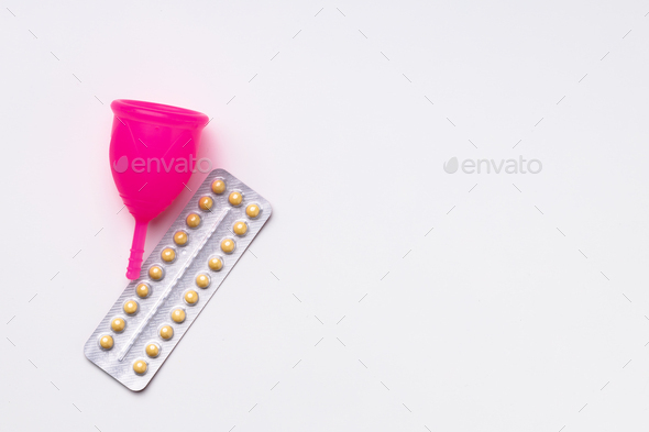 Menstrual cup and oral contraceptive pills top view Stock Photo by ...