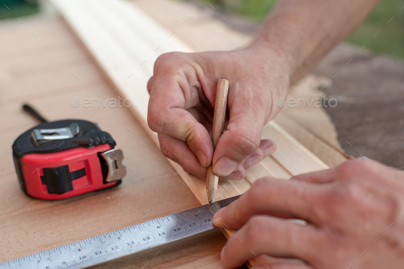 Carpenter hands take measurements with metal ruler on wooden board and ...