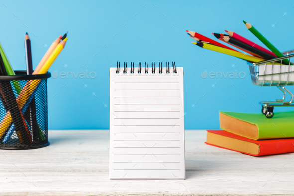 School supplies on wooden desk against blue background Stock Photo by ...