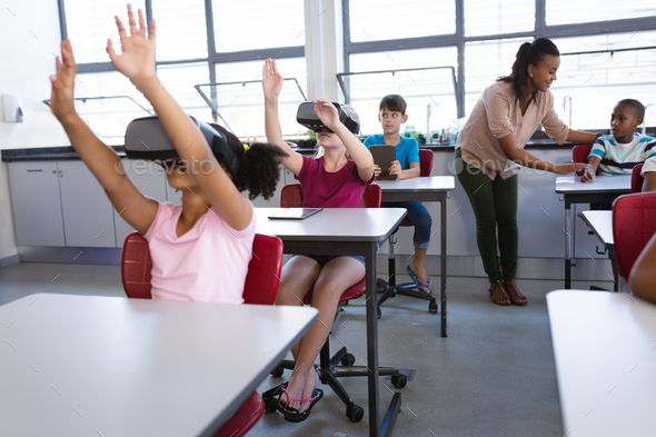 Group of diverse students using electronic devices while sitting on ...