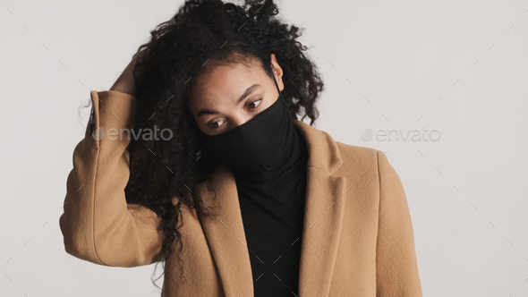 Afro American woman wearing black protective mask over white background ...