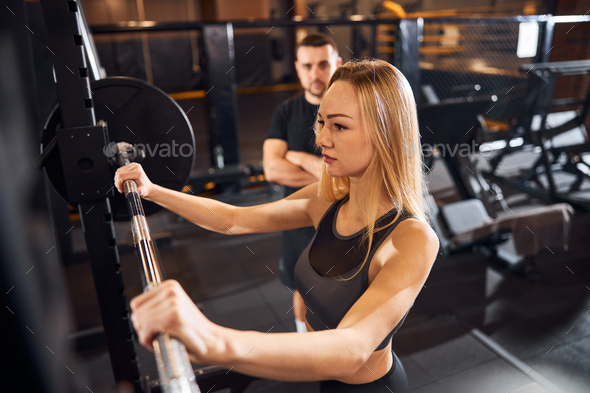 Hard-working lady working out at gym with help of coach Stock Photo by ...