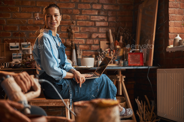 Brunette Caucasian craft woman sitting on the chair while posing at the ...