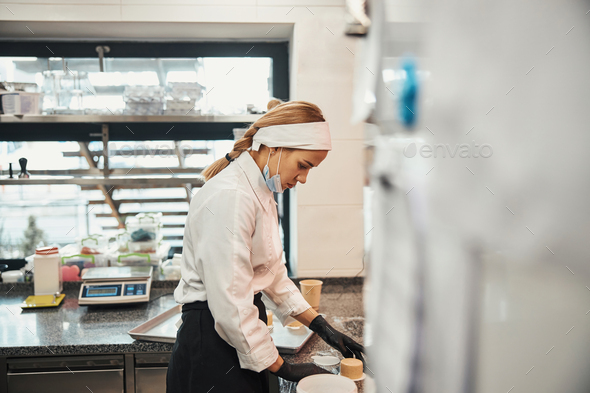 Focused woman in cook uniform looking busy in the kitchen Stock Photo ...