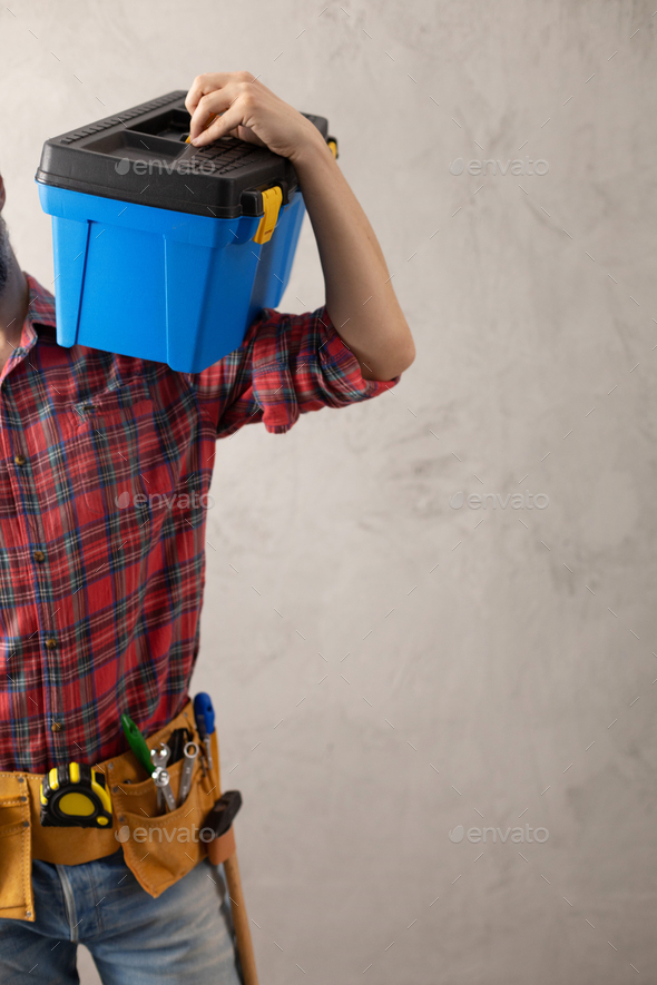 Man worker holding toolbox and tool belt near wall. Male hand and ...