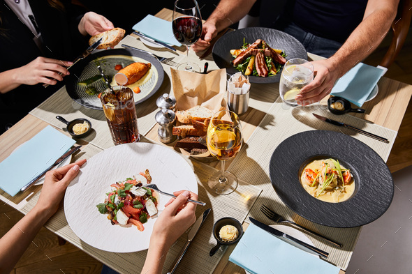 cropped view of people eating delicious food during dinner in ...