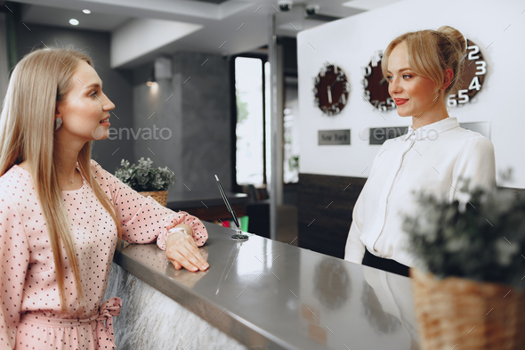 Blonde woman hotel guest checking-in at front desk in hotel Stock Photo ...