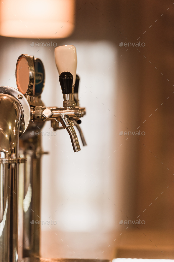 Beer taps at bar counter at the restaurant Stock Photo by LightFieldStudios