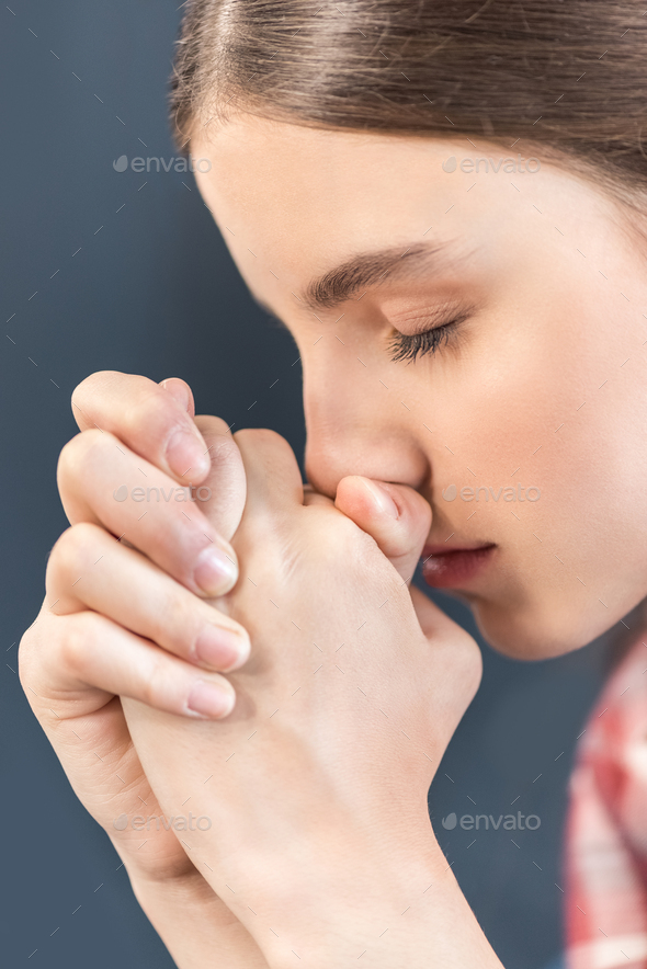 side view of beautiful pensive caucasian teenage girl praying with ...