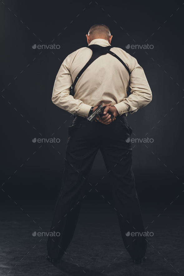 back view of killer in shirt holding gun behind back Stock Photo by ...
