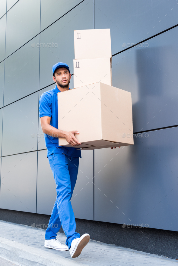 walking delivery man with stack of cardboard boxes Stock Photo by ...