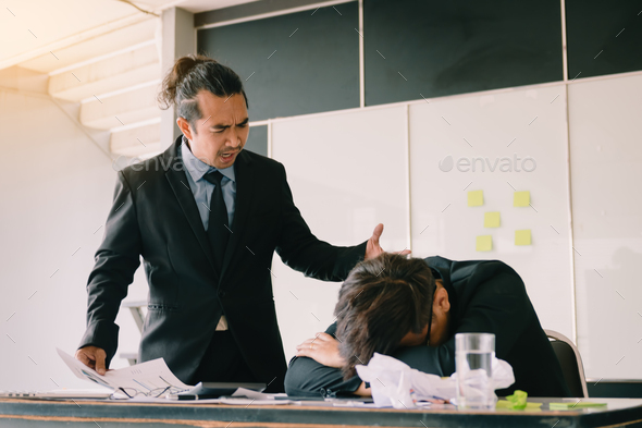 Boss reprimanding an employee in an office. Stock Photo by wutzkoh