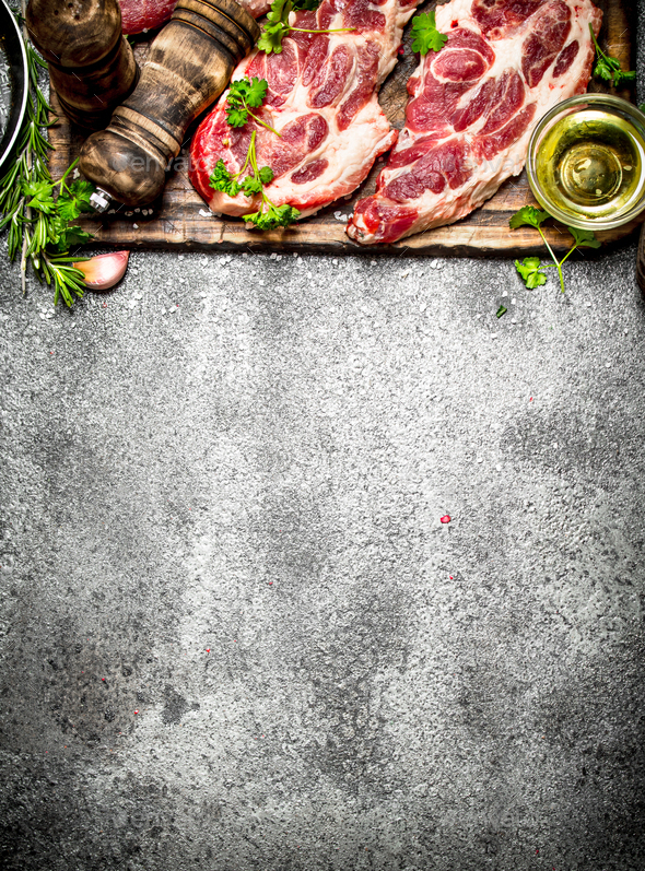 Raw meat background. Raw steak with herbs and spices on the old Board ...