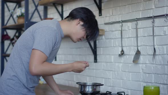 Side View of Young Asian Man Smelling Food in Cooking Pan on Stove ...