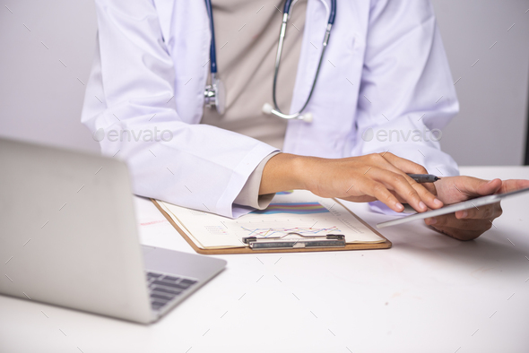 Doctor working with laptop computer and writing on paperwork. Hospital ...