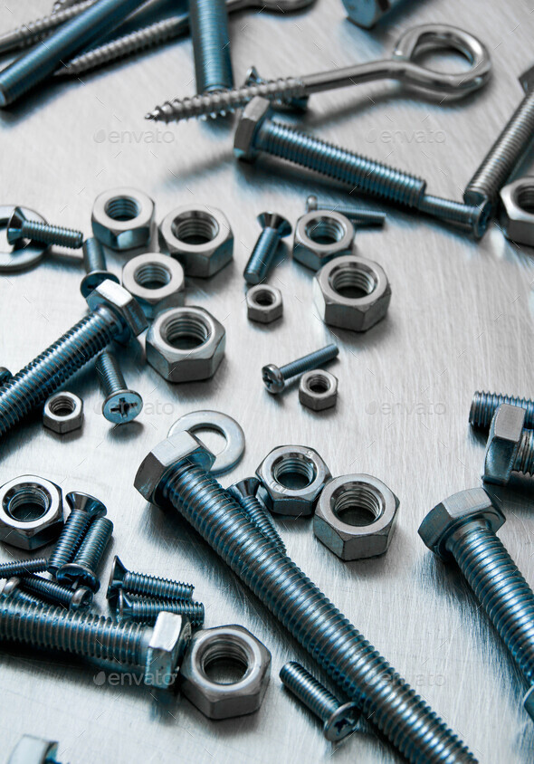 Fixing elements. Nuts, washers and bolts on scratched metal background ...