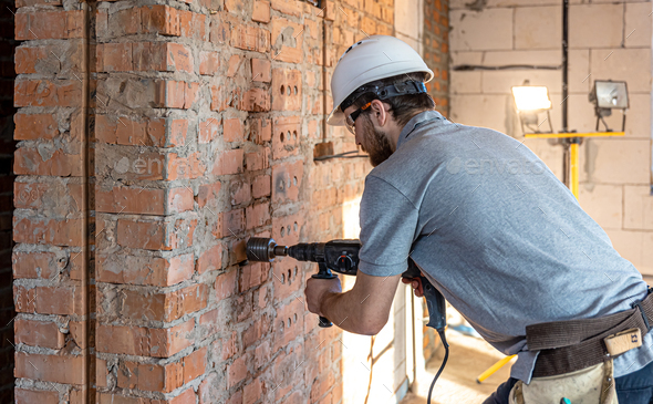 The builder works with a drill in working form. Stock Photo by puhimec