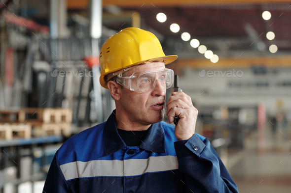 Mature factory foreman using radio device Stock Photo by Pressmaster