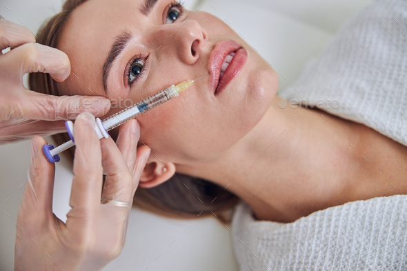 Focused elegant woman getting filler in syringe in beauty center Stock ...