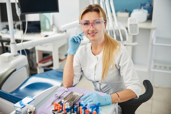 Relaxed female medic putting arms on instrument table Stock Photo by ...