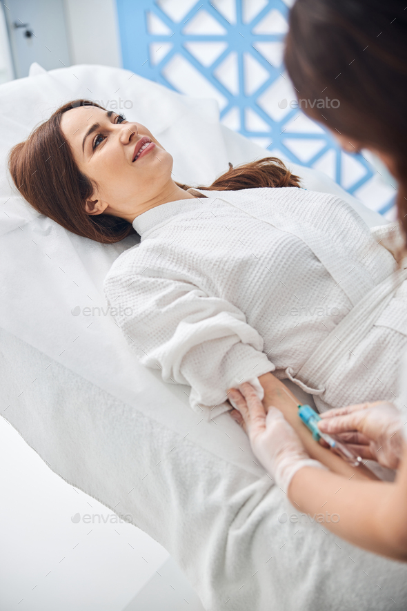 Beautiful woman receiving arm injection in clinic Stock Photo by Iakobchuk