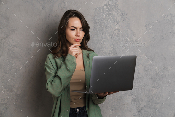 Puzzled beautiful brunette girl thinking and using laptop Stock Photo ...