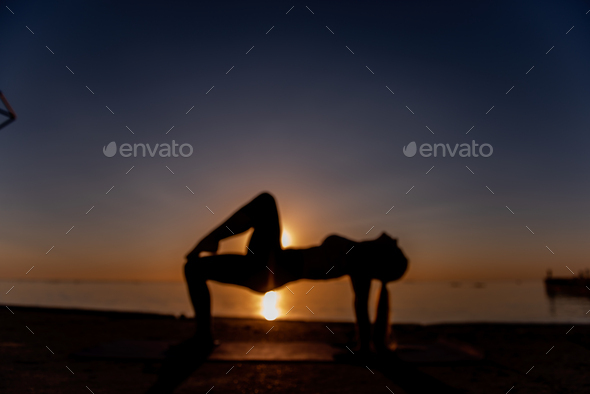 Defocused Young woman performs yoga asanas, Reverse bridge pose on the ...