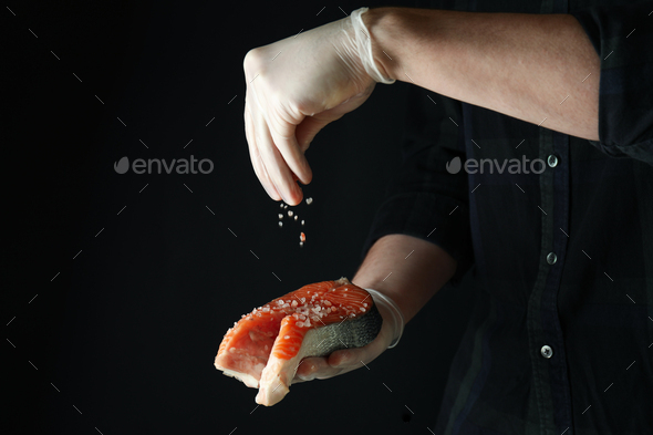 Man sprinkle salt on salmon meat on dark background Stock Photo by ...