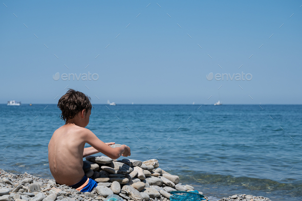 Child playing with rocks on the beach Stock Photo by Gajus-Images ...