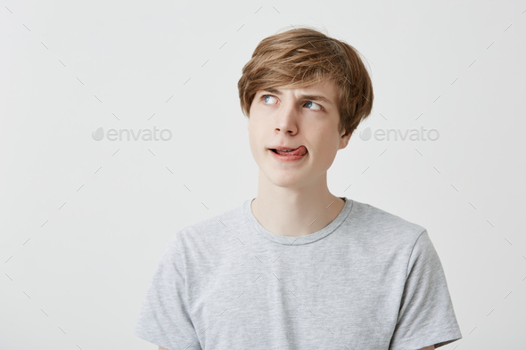 Indoor shot of young caucasian male student has puzzled expression ...