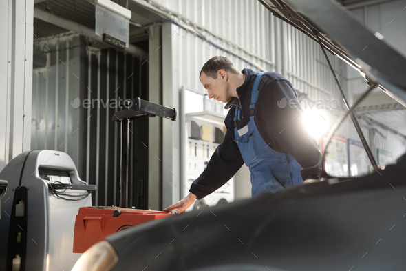 Mechanic checking of the headlights with a headlight tester device ...