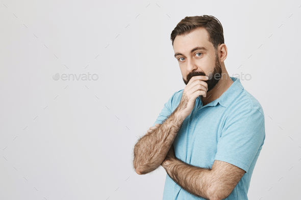 Picture of man looking curious touching his beard standing next to the ...