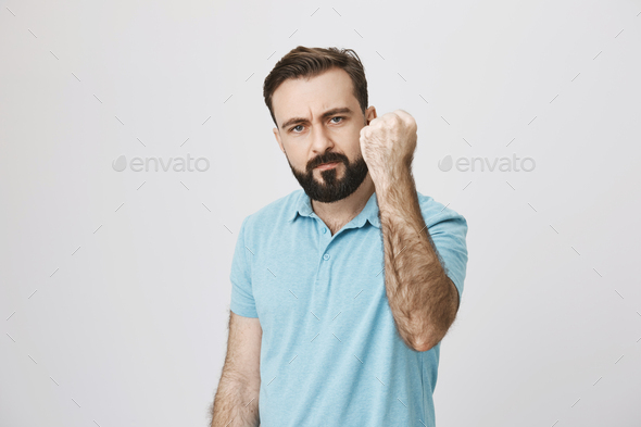 Portrait of mature handsome looking male holding his hand up wearing ...