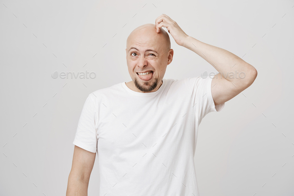 Indoor portrait of funny bald caucasian male scratching head while ...