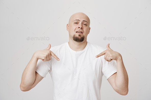 Portrait of smug and confident bald caucasian man pointing down while ...