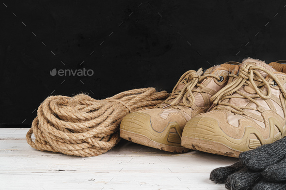 Hiking boots and rope hank on wooden board Stock Photo by FabrikaPhoto