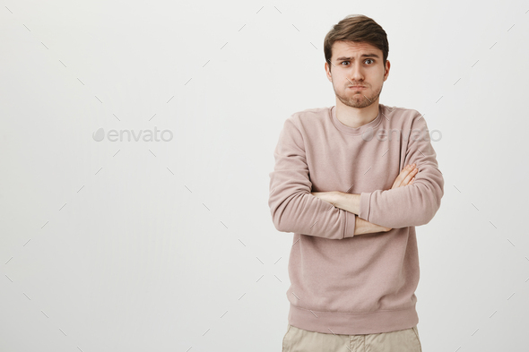 Studio portrait of cute young caucasian male standing with crossed ...