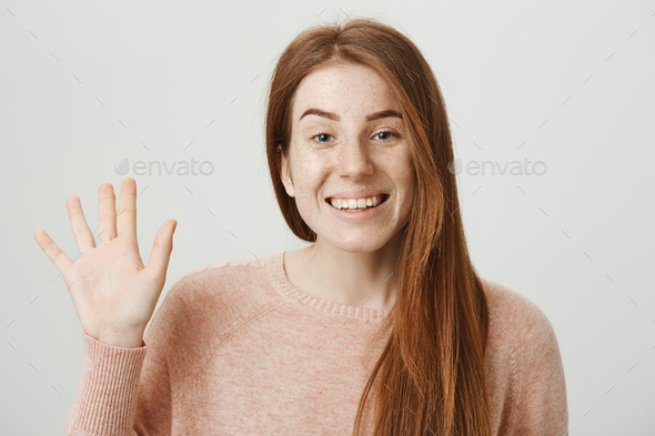 Close-up portrait of cute ginger girl waving with hand and smiling ...