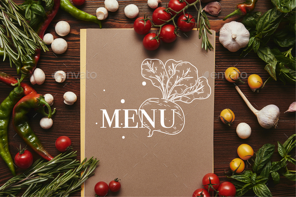 top view of menu and fresh vegetables with herbs on wooden surface ...