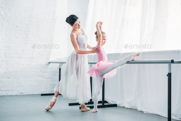 young ballet teacher exercising with cute little student in ballet ...
