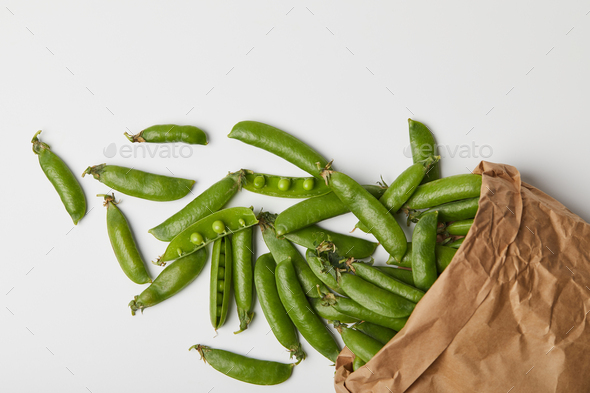top view of ripe pea pods spilled from paper bag on white surface Stock ...