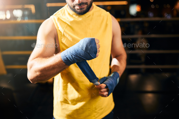Athletic man wrapping his arm into boxing wraps Stock Photo by Iakobchuk
