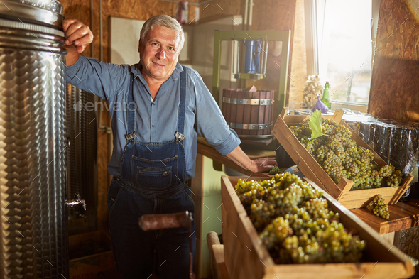 Happy winemaker posing near a water container at a winery Stock Photo ...