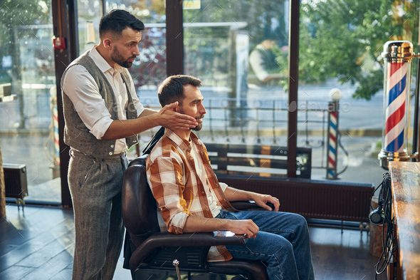 Professional barber adjusting head positioning of his client Stock ...