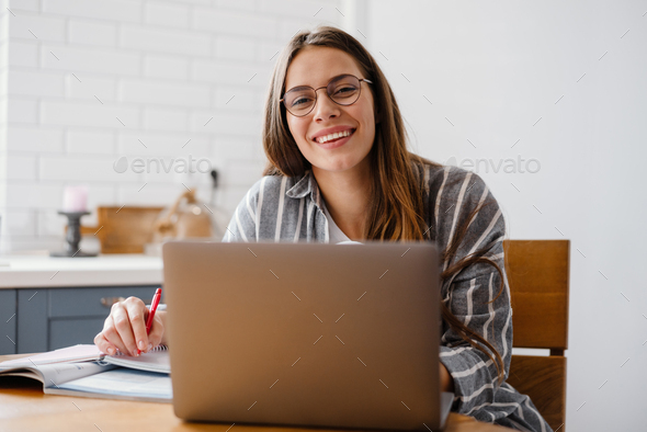 Cheerful beautiful woman doing homework with laptop Stock Photo by ...