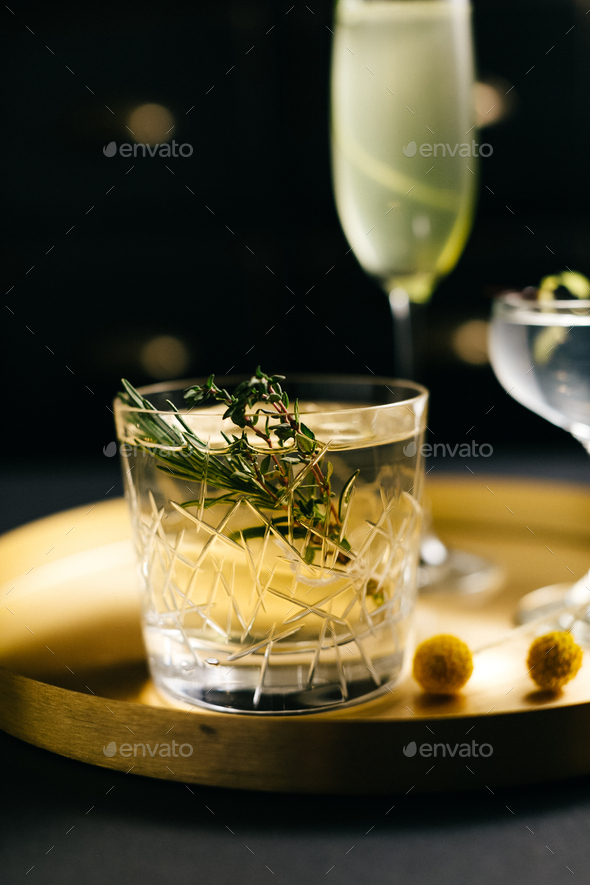 Bartender make drinks. Transparent cocktails in glass on dark ...