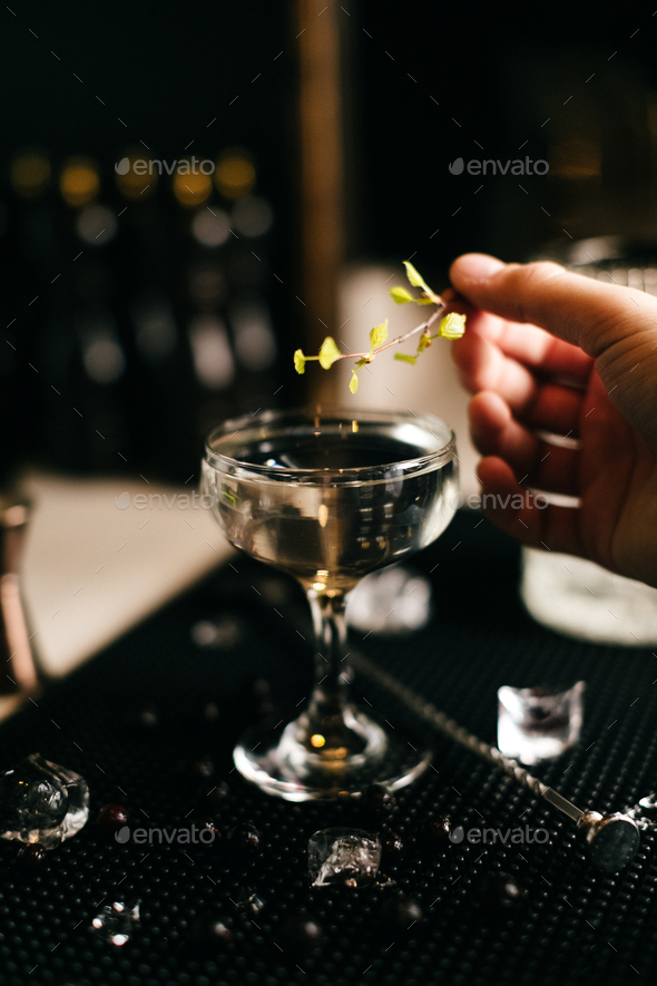 Bartender make drinks. Transparent cocktails in glass on dark ...